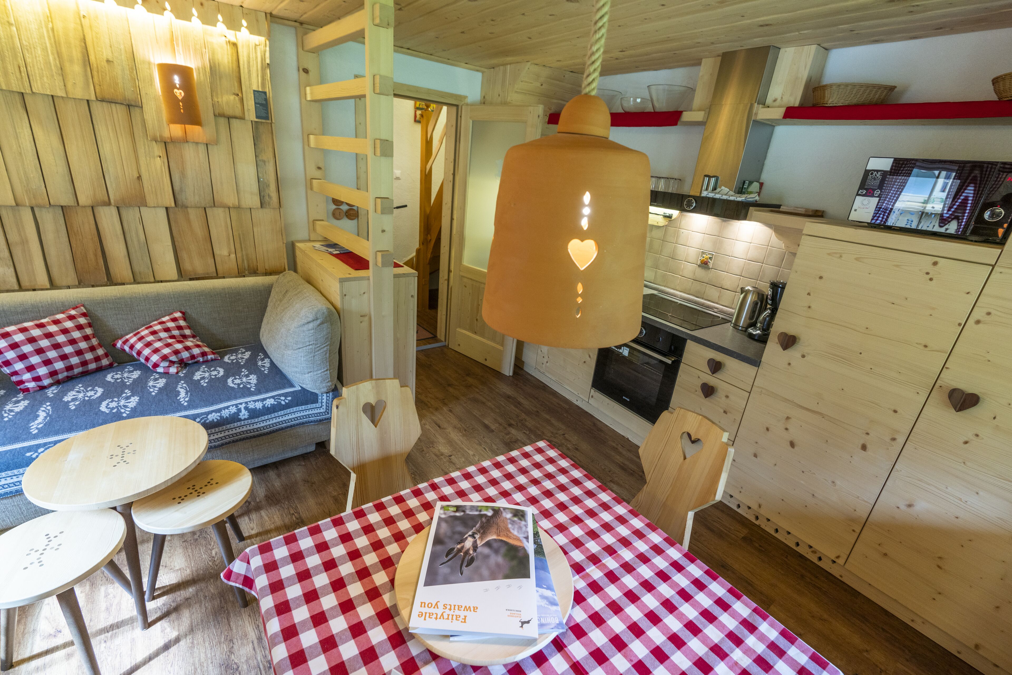 Um quarto acolhedor com uma mesa xadrez, um sofá com almofadas estampadas e um lustre.
