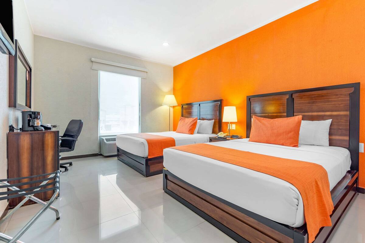 Quarto de hotel com duas camas, uma escrivaninha e uma cadeira.