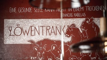 Uma parede com um desenho de giz de um gato e um cachorro, e o texto "ZÖWENTRANK" e "EINE GESUNDE SEELE KANN NICHT IN EINEM TROCKENEN FRANCOIS RABELAIS".