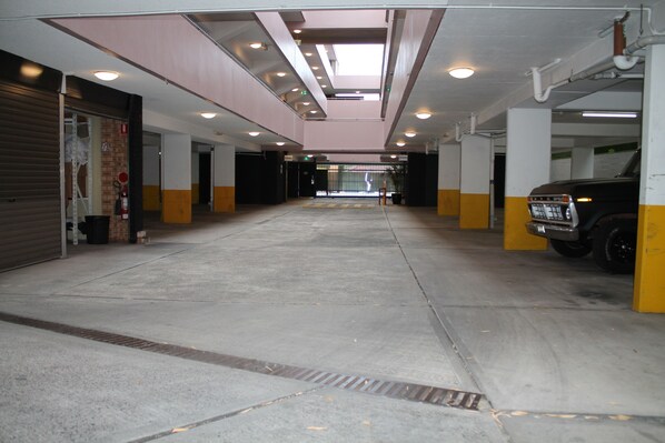 Um estacionamento com vários níveis, pisos de concreto e pilares amarelos.