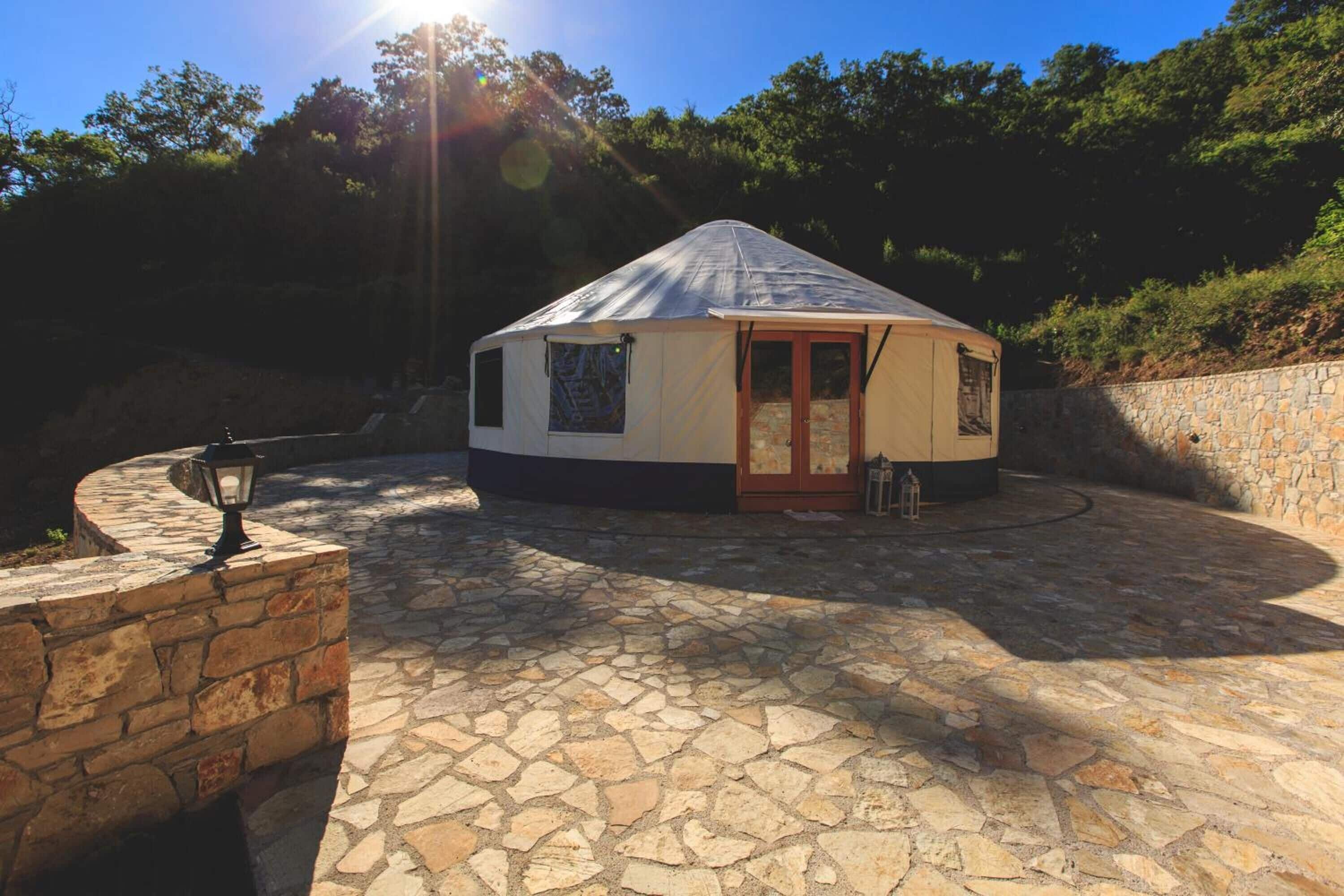 Uma yurta com um pátio de pedra, uma parede de pedra e um poste de luz.