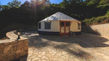 Uma yurta com um pátio de pedra, uma parede de pedra e um poste de luz.