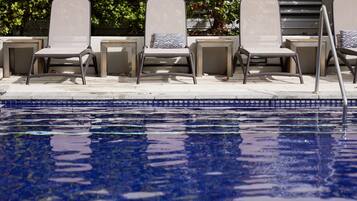 Uma área na beira da piscina com espreguiçadeiras e uma piscina pequena.