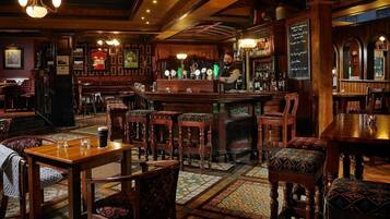 Um pub tradicional com móveis de madeira, área de bar e chão estampado.