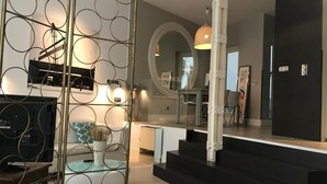 Uma sala de estar moderna com um sofá seccional, uma mesa de centro e uma TV. Há uma escada que leva a outro nível.
