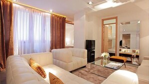 Uma sala de estar moderna com um conjunto de sofás, uma mesa de centro e uma televisão.