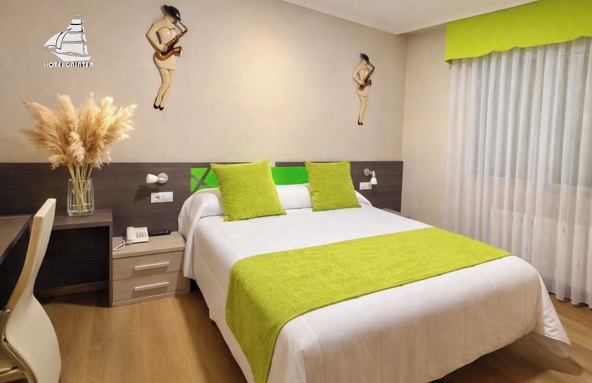 Quarto de hotel com cama, mesas de cabeceira, escrivaninha, cadeira e arte decorativa na parede.