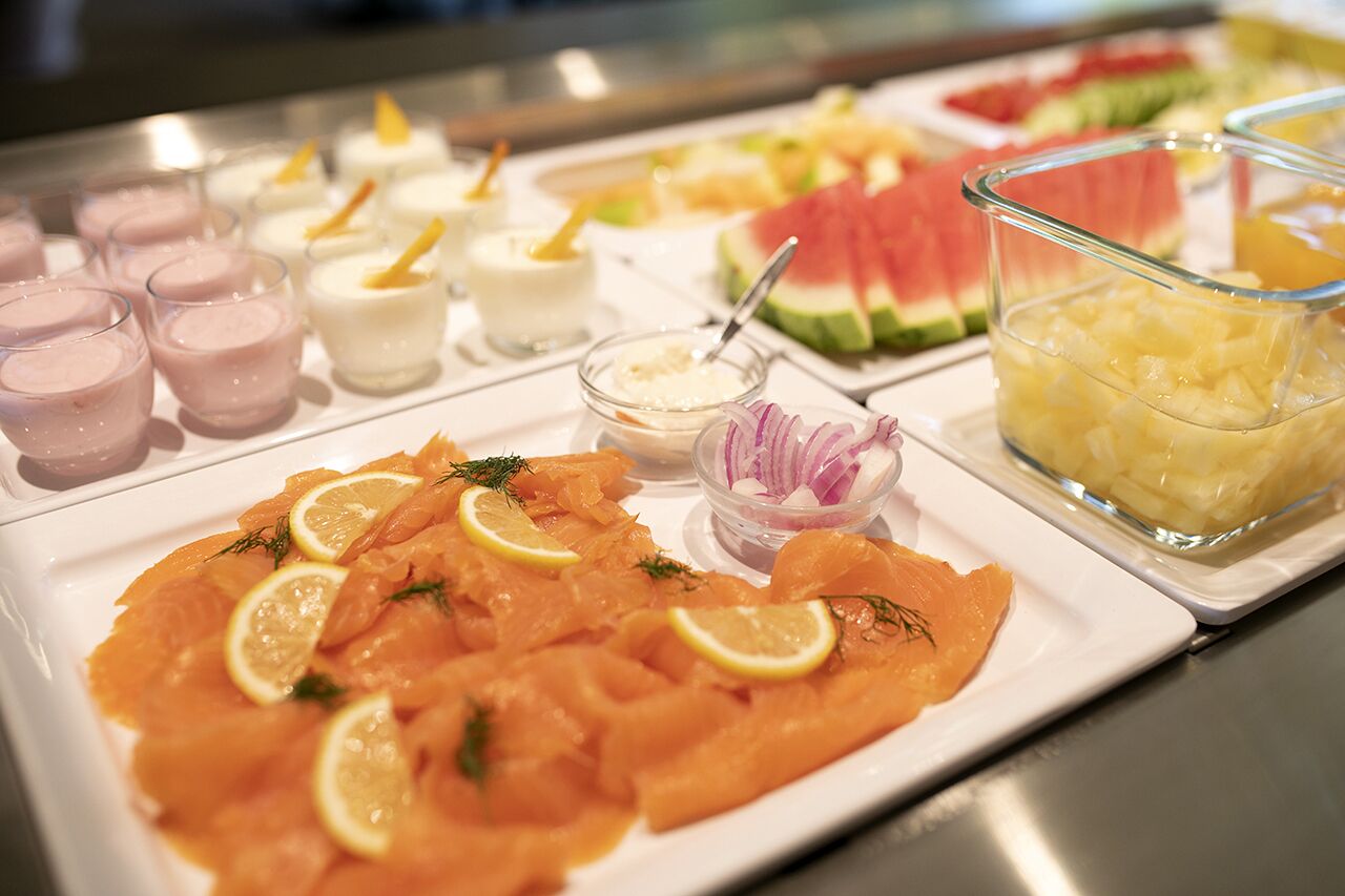 Buffet com salmão, frutas e diversos molhos.