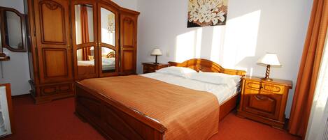Quarto com cama de madeira, guarda-roupa, duas mesas de cabeceira com luminárias e uma grande obra de arte floral na parede.