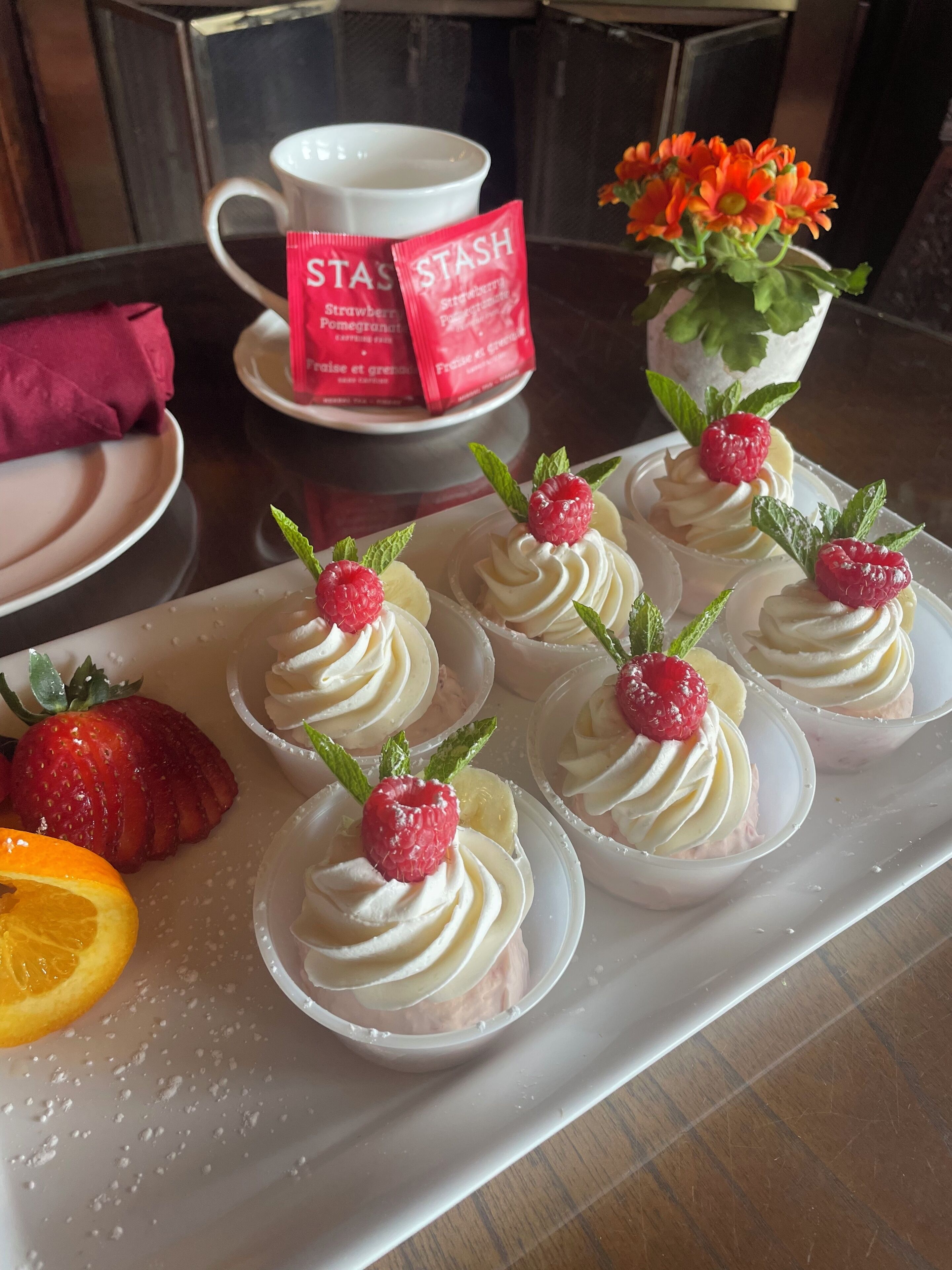 Uma bandeja de sobremesas com chantilly e frutas, uma xícara de café e um pacote de morangos.