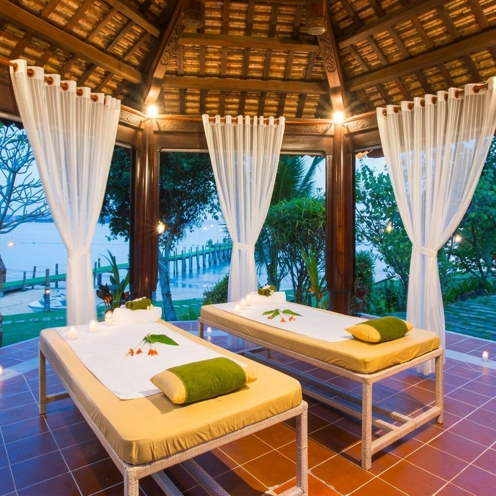 Uma área de spa com duas mesas de massagem, cortinas brancas e vista para uma ponte e vegetação.