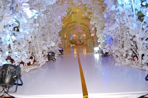 Corredor decorado com flores brancas e uma faixa dourada no centro do chão.