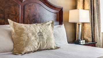 Uma cama bem arrumada com travesseiro decorativo, abajur e cabeceira de madeira.