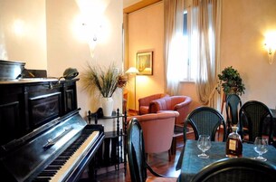 Um quarto com um piano, uma mesa de jantar com cadeiras, um abajur e uma planta.