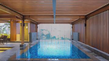 Piscina com 14 metros de comprimento, cercada por painéis de madeira e área coberta com assentos.