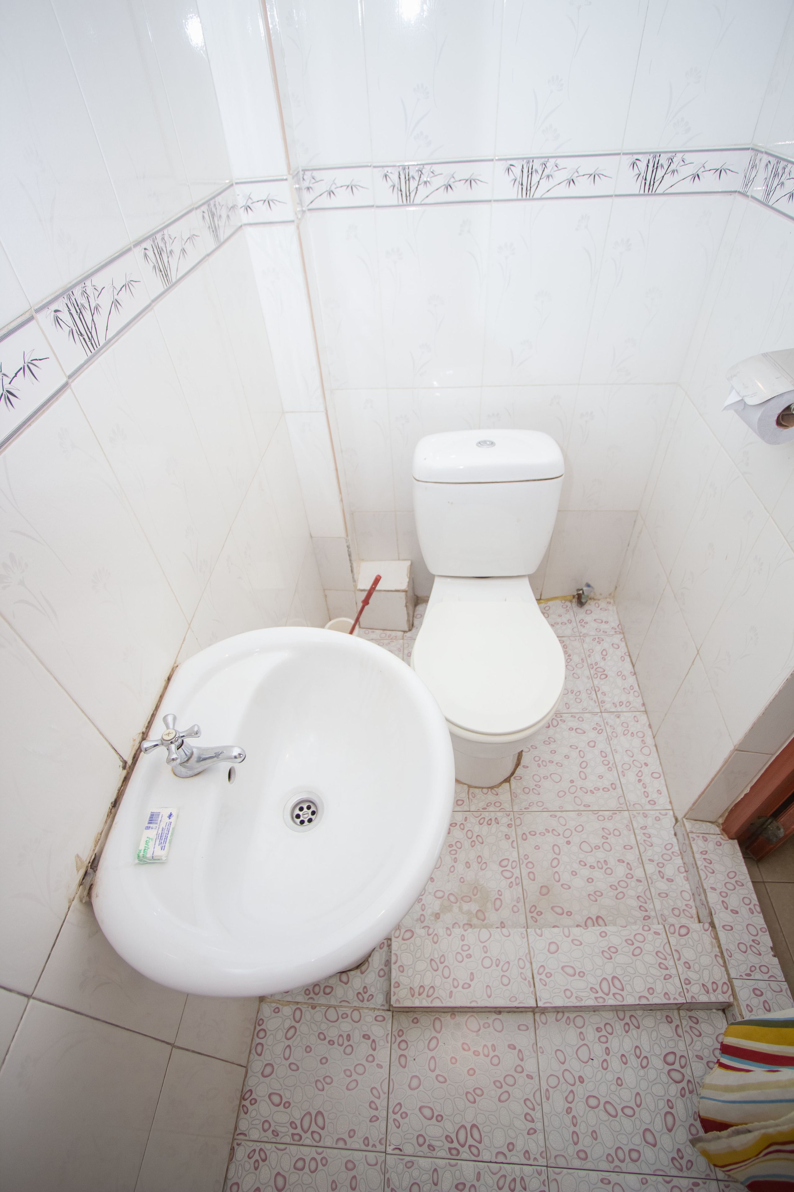 Casa de banho com sanita, lavatório e azulejos estampados.