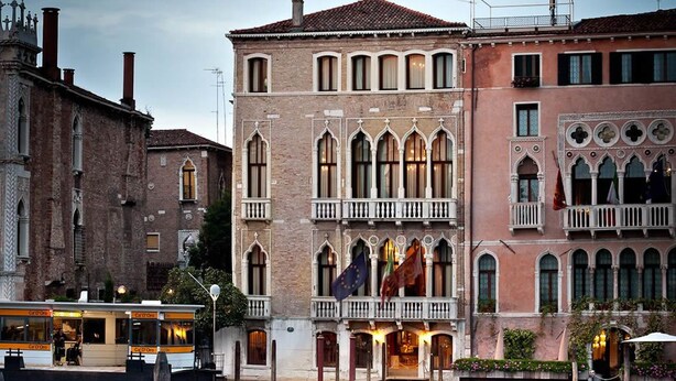 Um edifício histórico veneziano com várias varandas e vista para um canal.