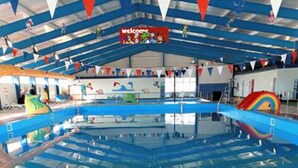 Piscina interna com piso azul, rodeada por paredes azuis e teto com bandeiras triangulares.