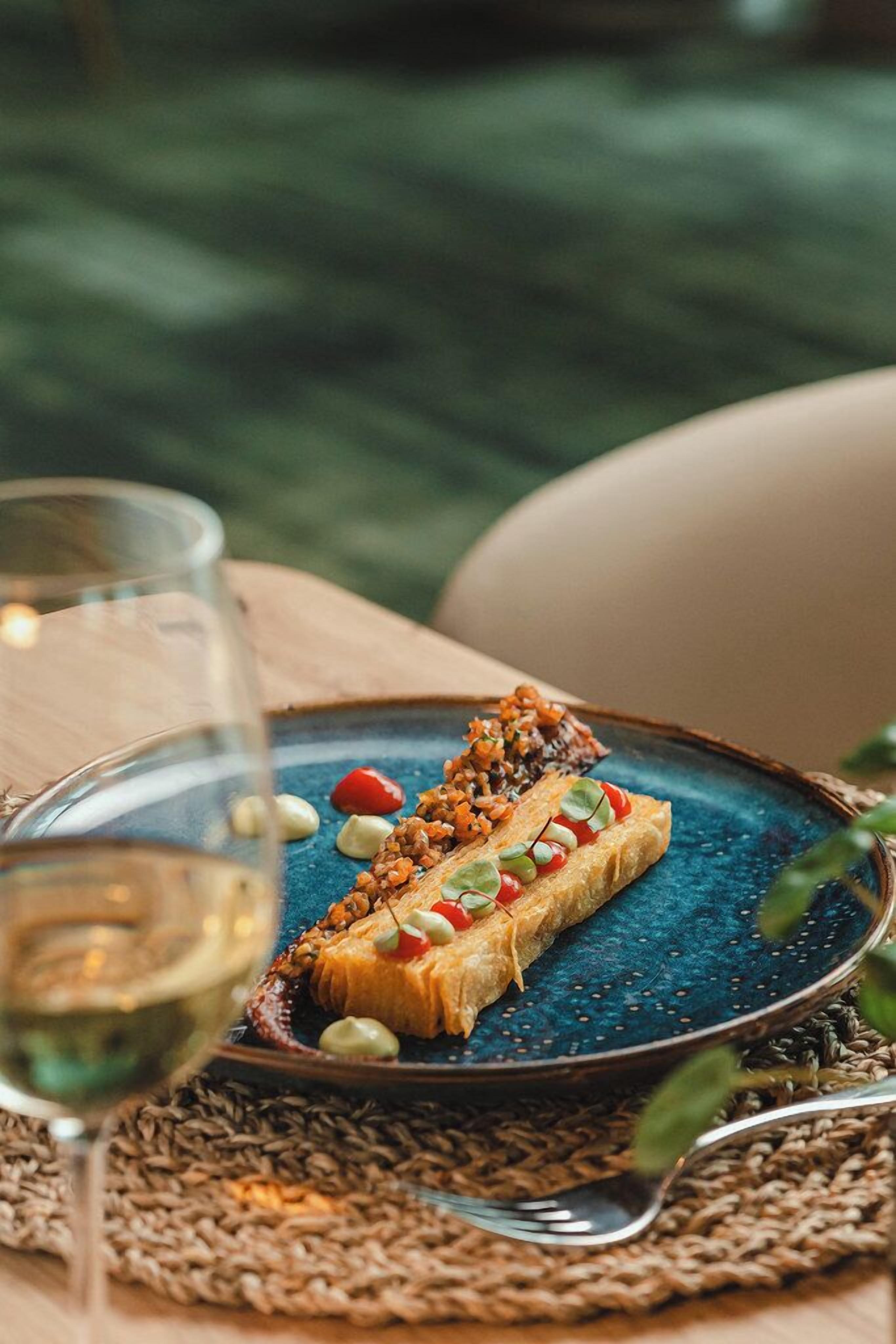 Prato de comida com um copo de vinho branco sobre um jogo americano de tecido.