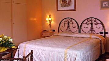 Um quarto com uma cama grande, uma cadeira de madeira, uma mesa de cabeceira com abajur e um quadro na parede.