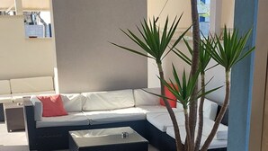 Um espaço interno moderno com um sofá branco, uma mesinha e um vaso de planta.