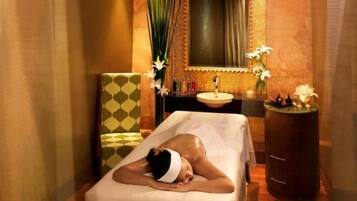 Sala de spa com mesa de massagem, pia e espelho.