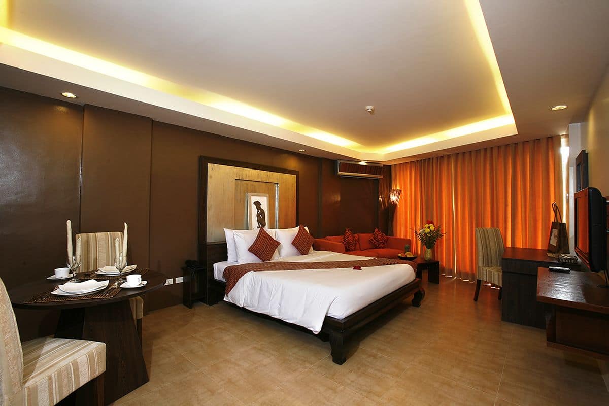 Quarto de hotel com uma cama grande, uma escrivaninha, uma cadeira e um espaço de refeições.