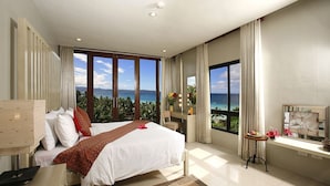 Quarto de hotel moderno com uma cama grande, uma escrivaninha e vista para o oceano.