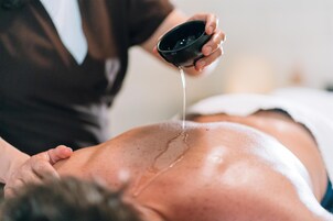 Uma pessoa recebendo massagem com uma tigela preta e um pano branco.
