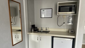 Uma cozinha compacta equipada com micro-ondas, pia e pequeno frigorífico.
