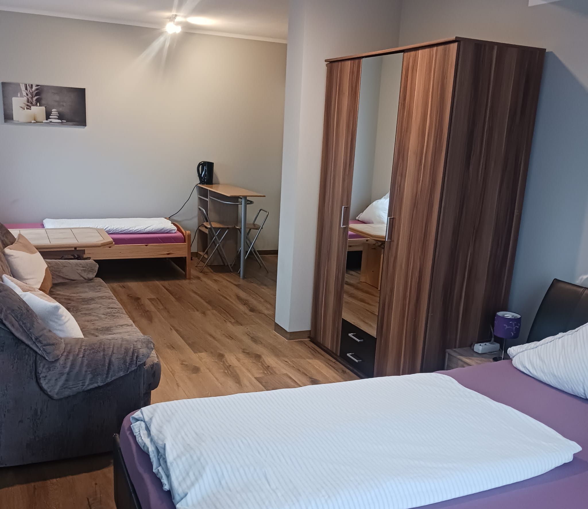 Quarto moderno com cama, sofá, escrivaninha e guarda-roupa.