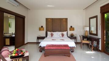 Quarto de hotel com uma cama grande, mesas de cabeceira, escrivaninha, cadeira, espelho e uma cesta de frutas.