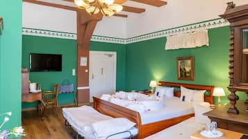 Quarto de hotel com duas camas, uma mesa com cadeira, televisão e teto de madeira.