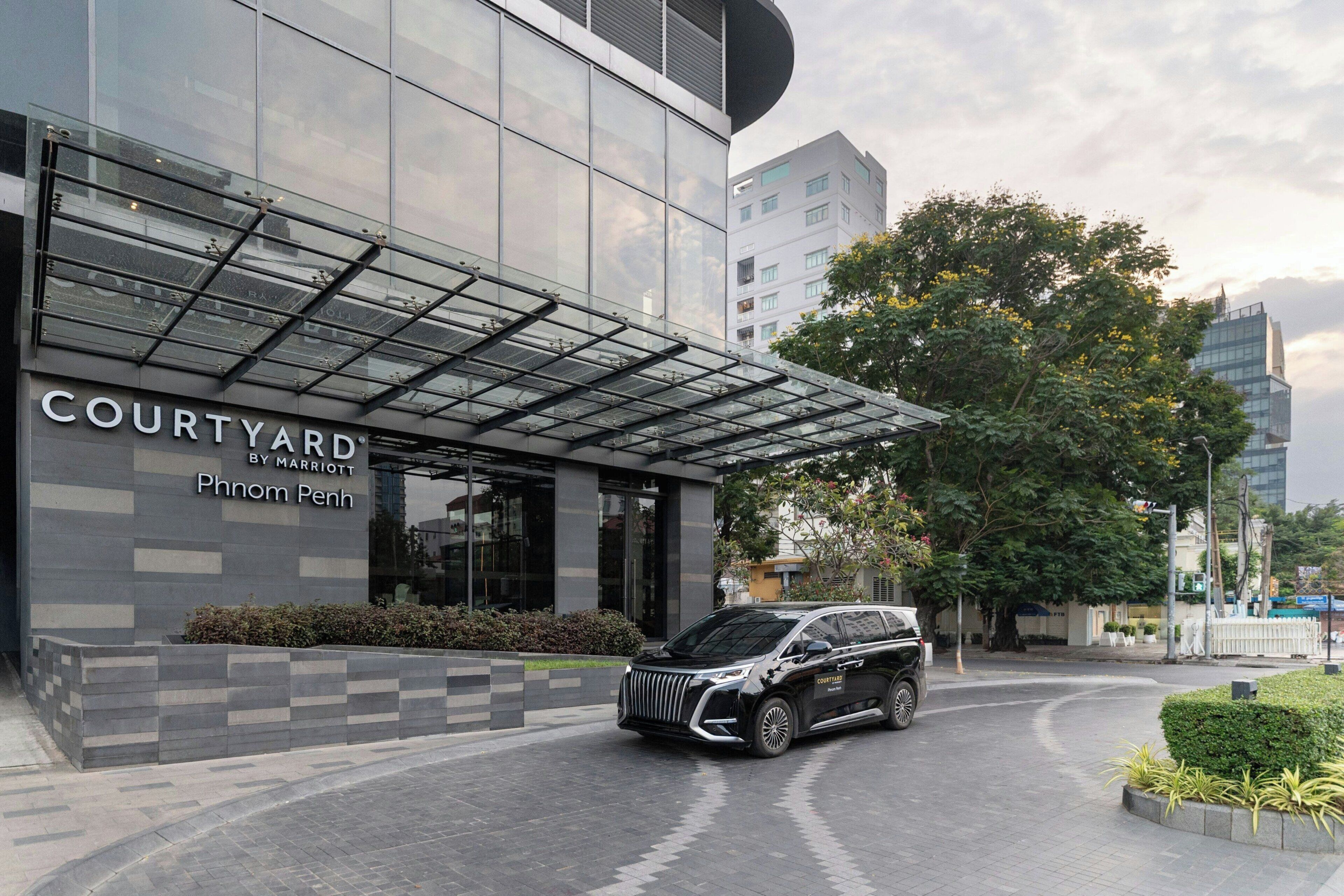 Um edifício moderno com fachada de vidro e uma placa que diz 'COURTYARD BY MARRIOTT Phnom Penh'.