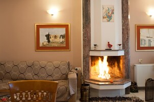 Uma sala de estar acolhedora com lareira, um sofá estampado e uma mesa de jantar.