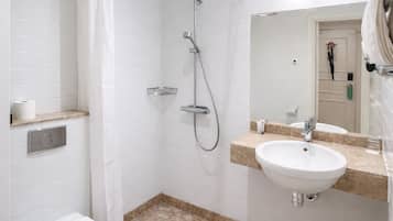 Uma casa de banho moderna com chuveiro, sanita e lavatório.