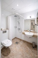 Uma casa de banho moderna com chuveiro, sanita e lavatório.