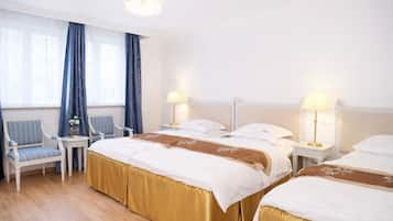 Quarto de hotel com duas camas, uma cadeira, uma mesa e um candelabro.