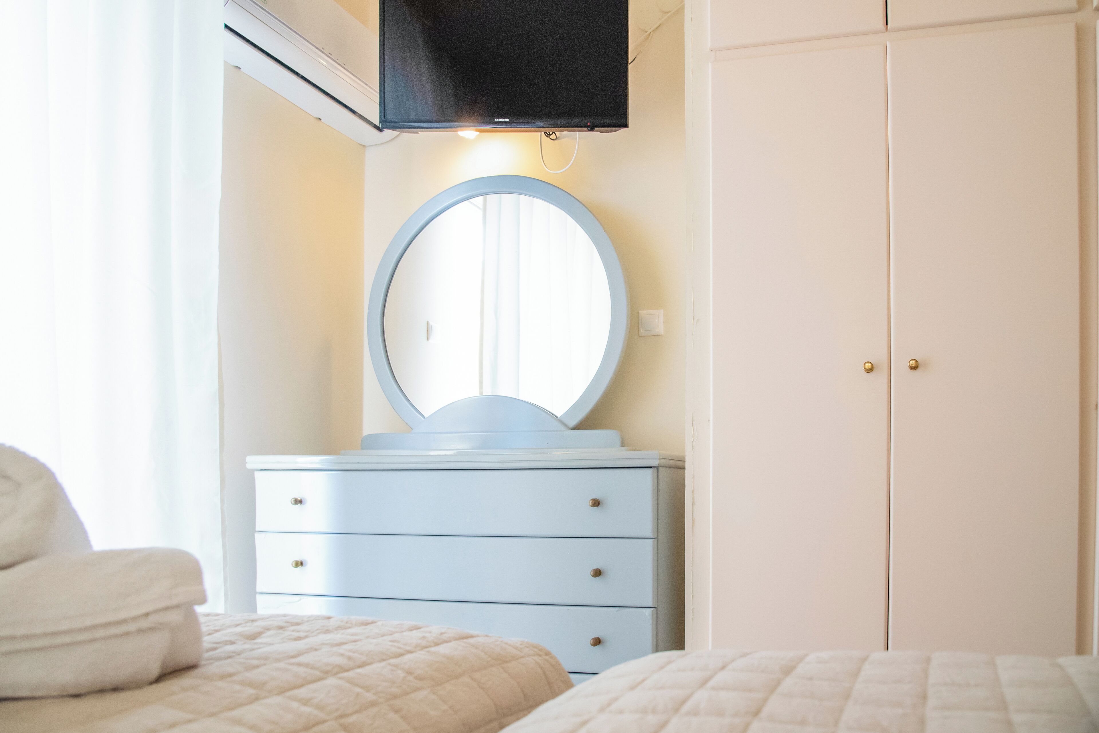 Quarto com uma cama, penteadeira com espelho e guarda-roupa.