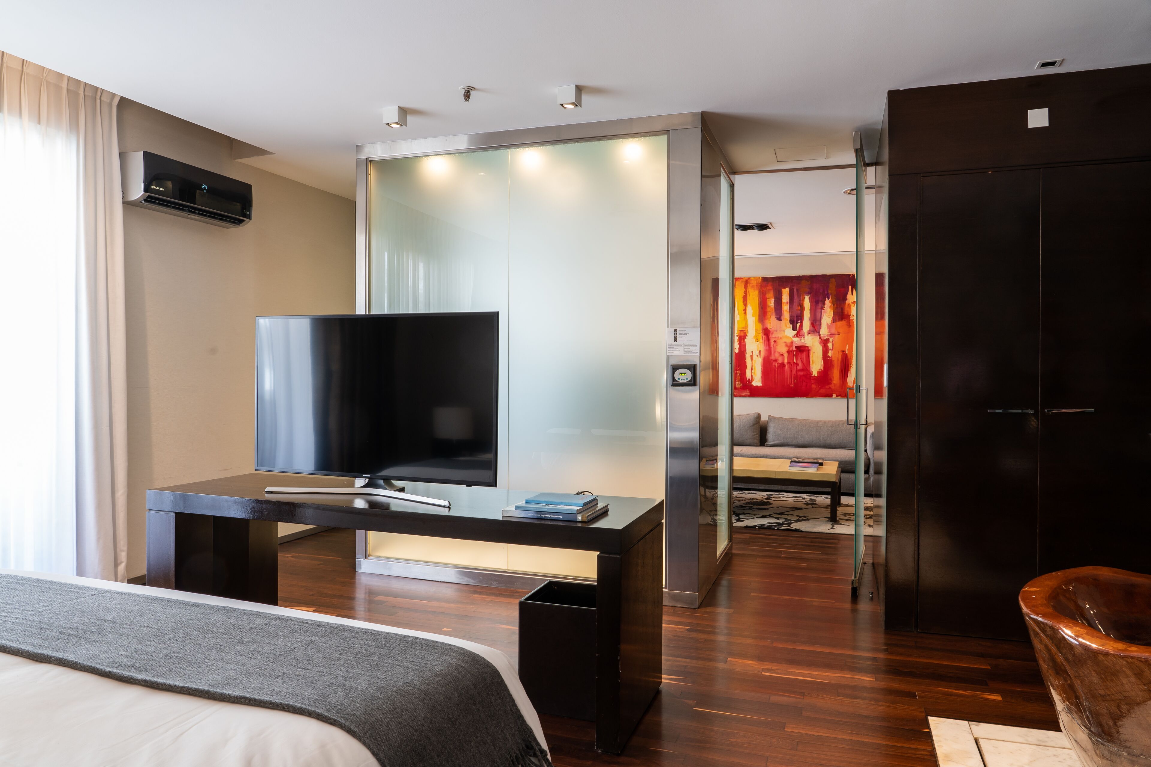 Quarto de hotel moderno com uma cama grande, televisão de tela plana, escrivaninha com computador e armário.