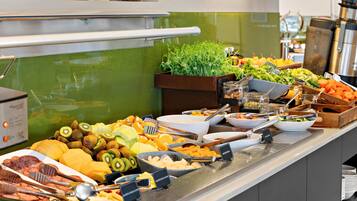 Buffet com diversas opções de comida, incluindo frutas, legumes e carnes.