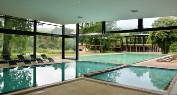 Uma piscina com água cristalina, rodeada por espreguiçadeiras e uma área de estar coberta.