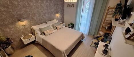 Quarto moderno com uma cama grande, mesas de cabeceira, escrivaninha e luminária pendente.