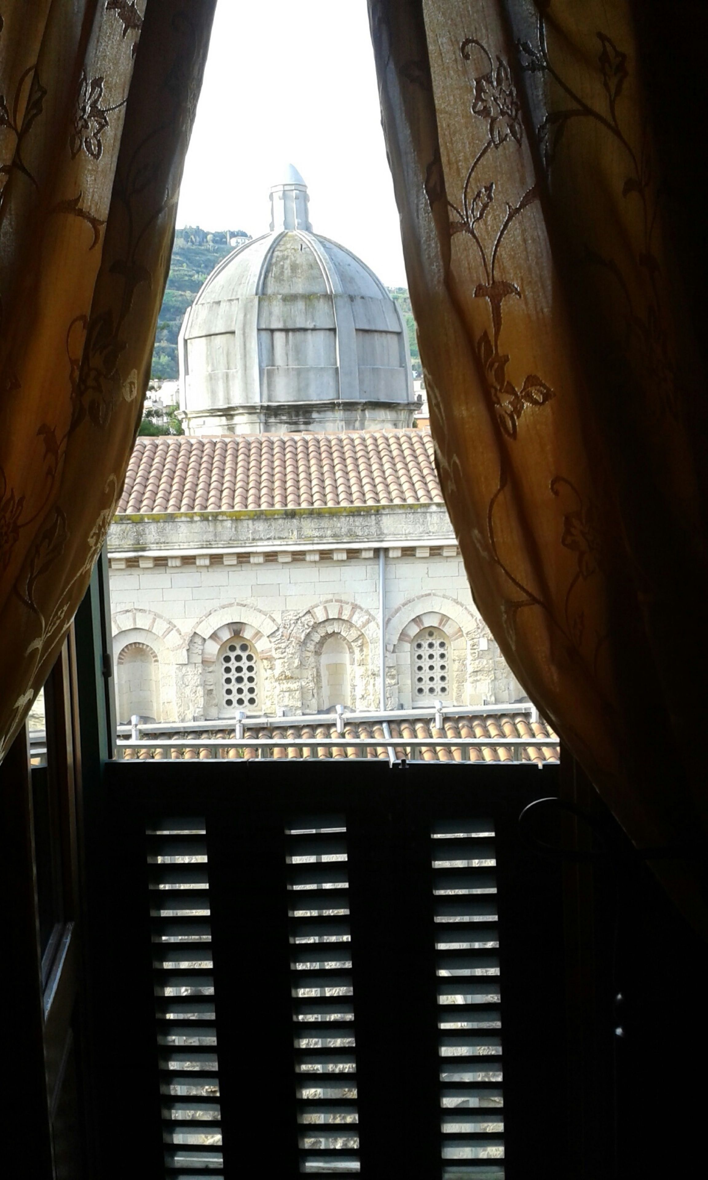 Vista de um edifício com cúpula vista através de venezianas.