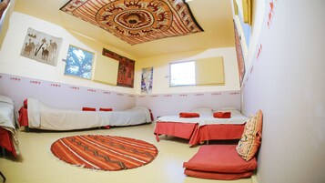 Quarto com duas camas de solteiro, um sofá, um tapete estampado e um teto com arte tradicional.