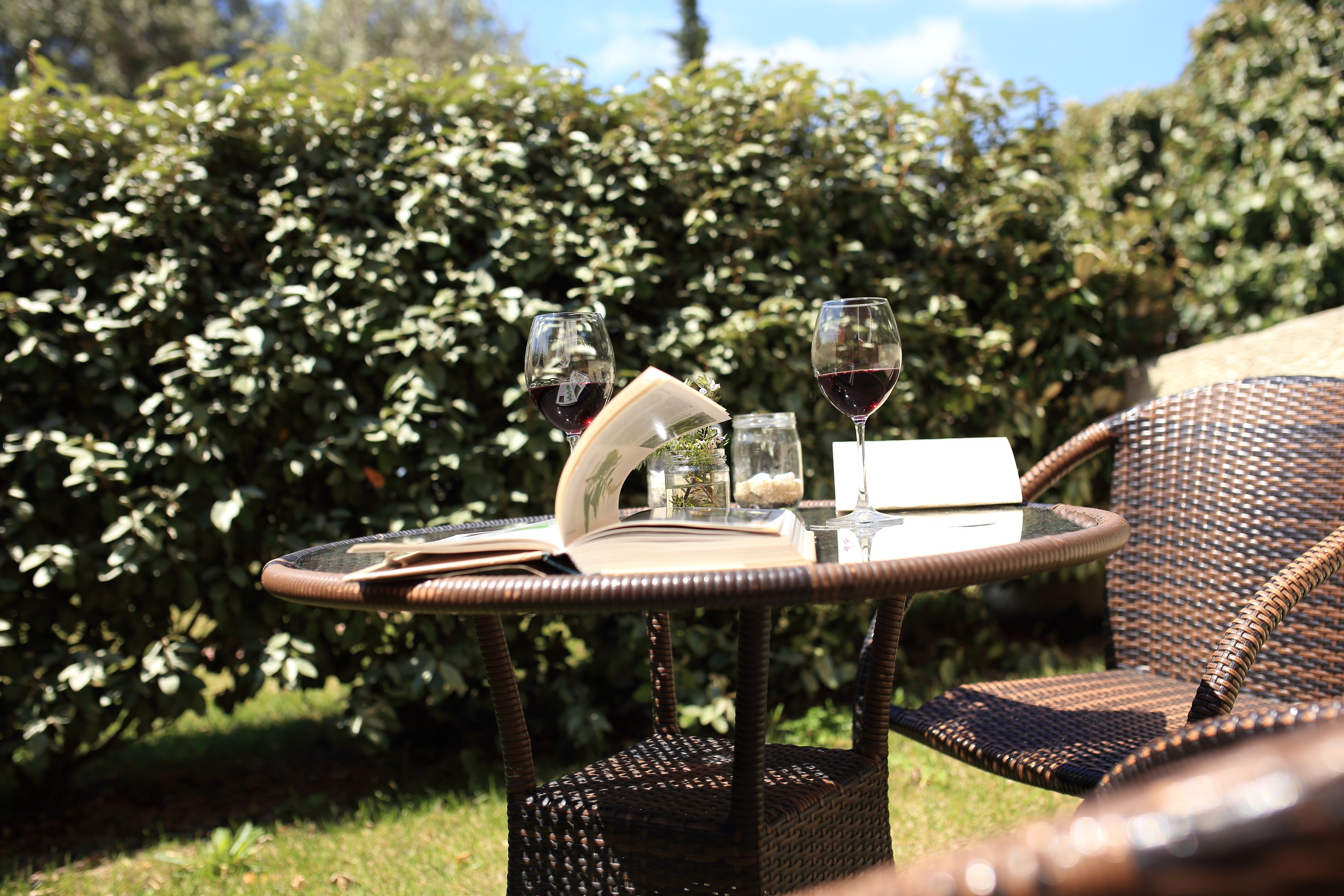 Uma mesa de vime com um menu, duas taças de vinho e um pequeno frasco de açúcar.