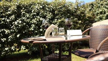 Uma mesa de vime com um menu, duas taças de vinho e um pequeno frasco de açúcar.