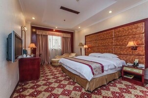 Quarto de hotel com uma cama grande, televisão, escrivaninha e uma cadeira.