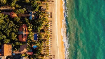 Na praia, areia branca, barracas de praia de cortesia, espreguiçadeiras 