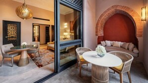 Interior moderno com porta de vidro que dá para um quarto, mesa de jantar redonda e área de estar aconchegante com um arco vermelho.